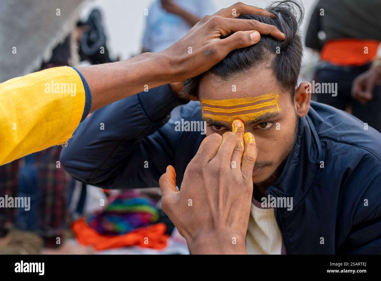 A Hindu devotee gets a sacred mark on his forehead after bathing at the ...