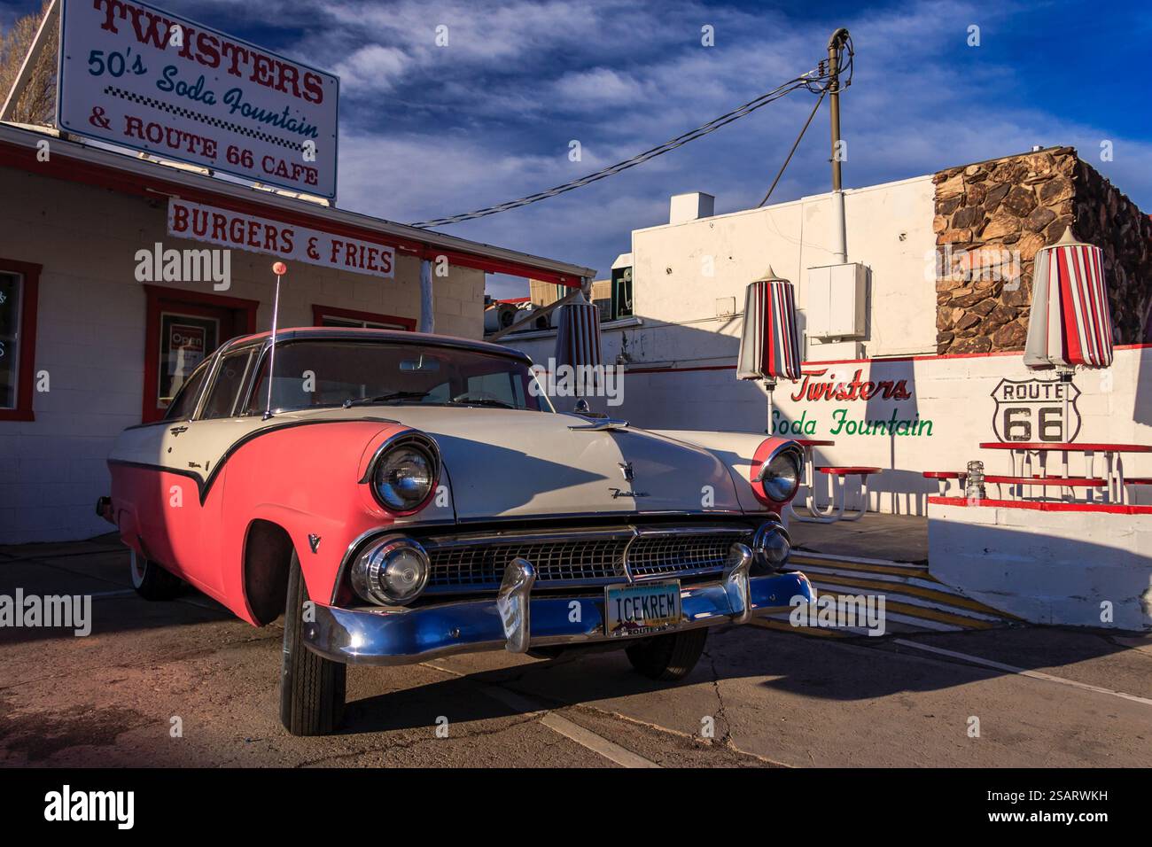 A vintage car is parked in front of a diner. The diner is called ...
