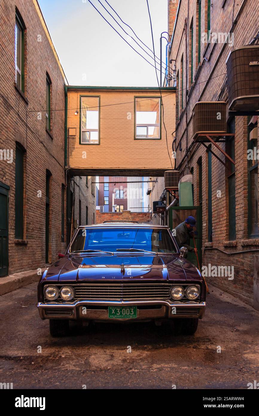 A vintage car is parked in a narrow alleyway. The car is a maroon color ...