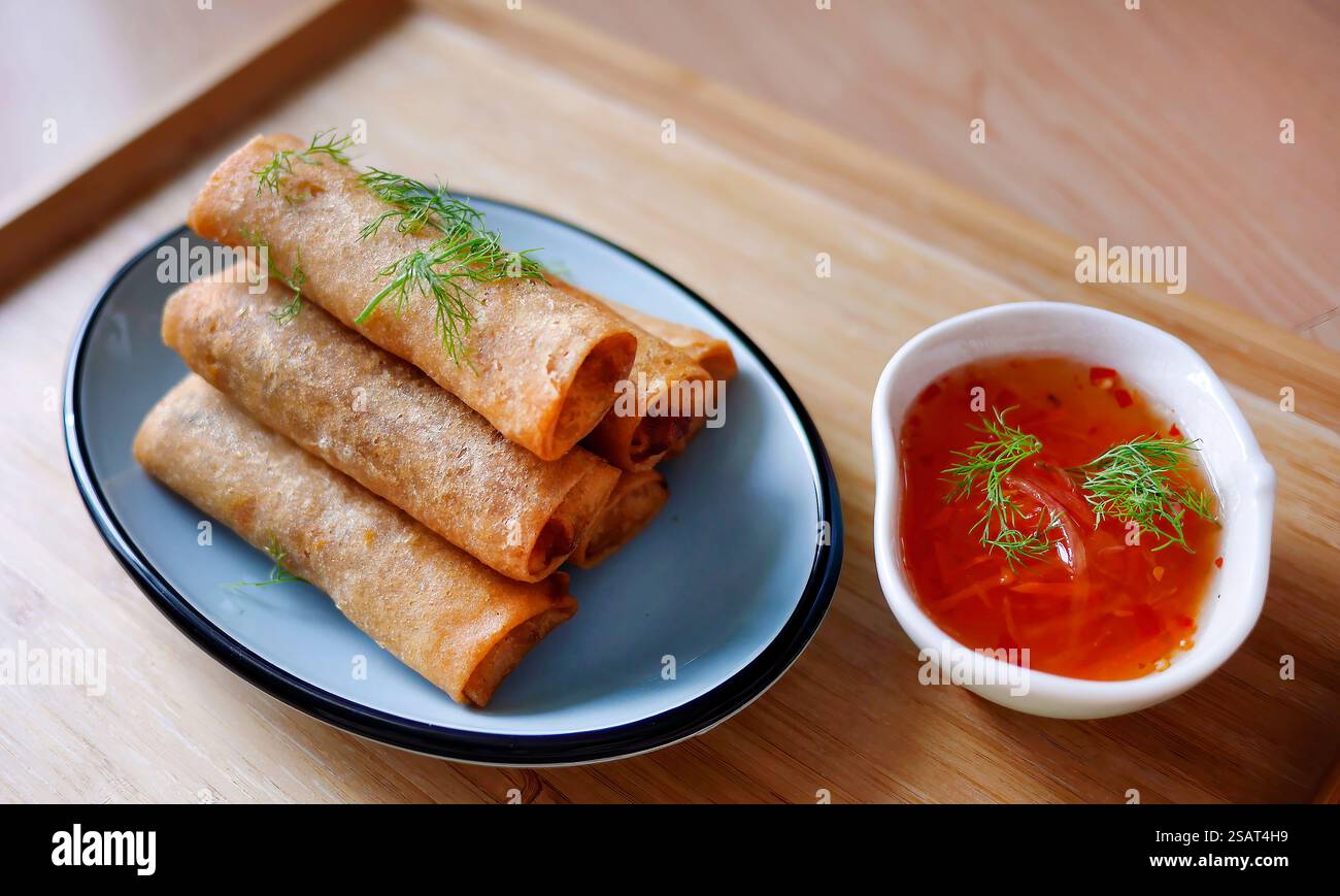 Deep fried spring roll in golden brown color, served in a blue oval shape plate, famous local ...