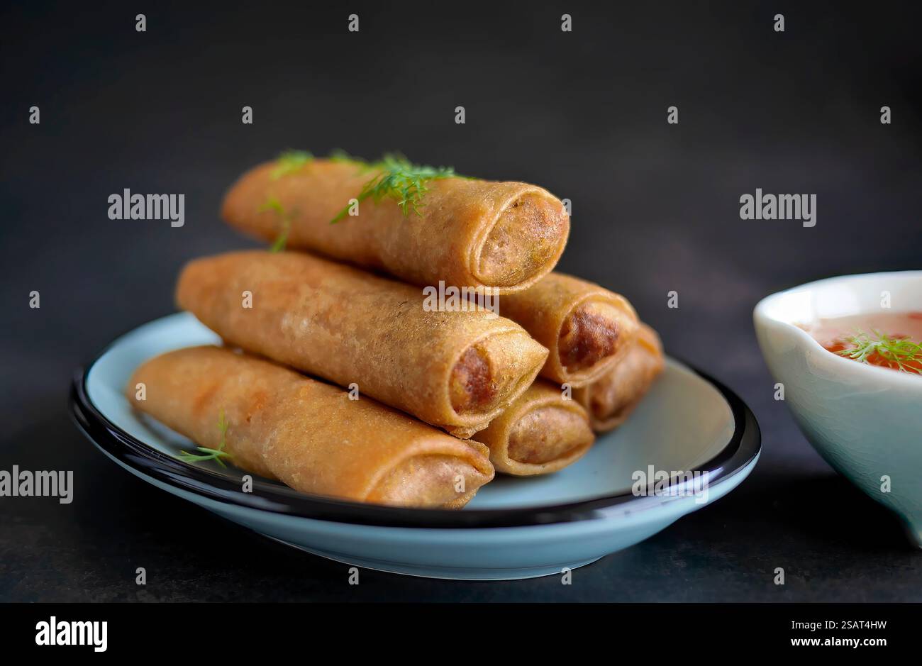 Deep fried spring roll in golden brown color, served in a blue oval shape plate, famous local ...