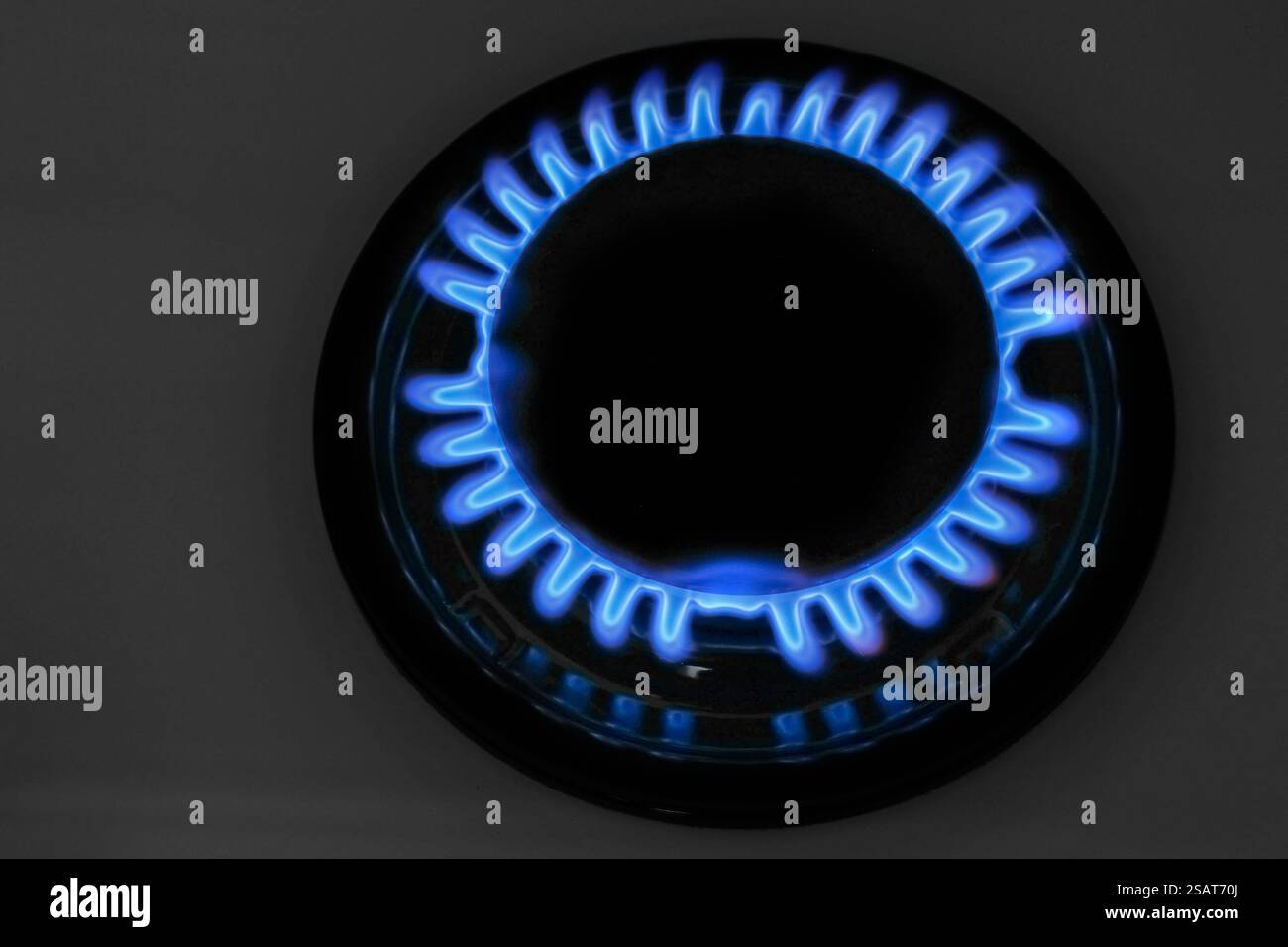 Gas burner of modern stove with burning blue flame at night, closeup ...