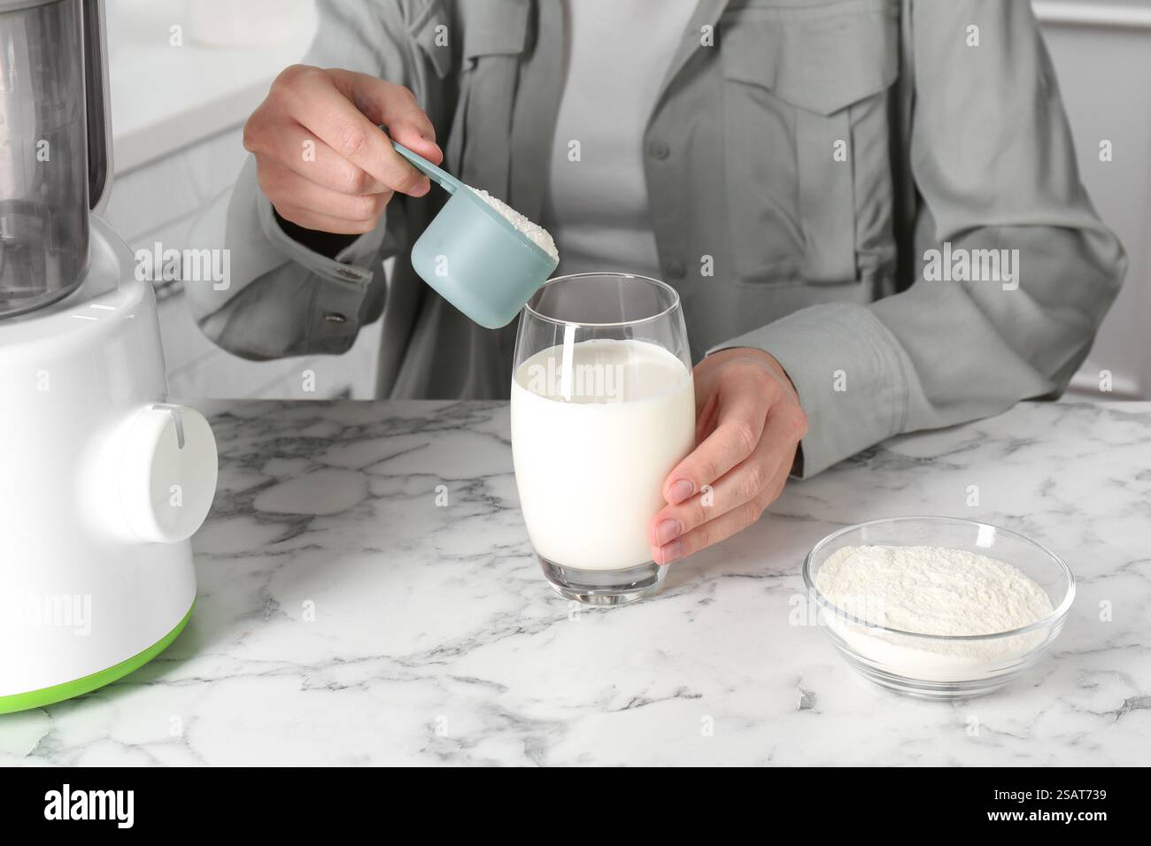 Making protein cocktail. Woman adding powder into glass with milk at ...