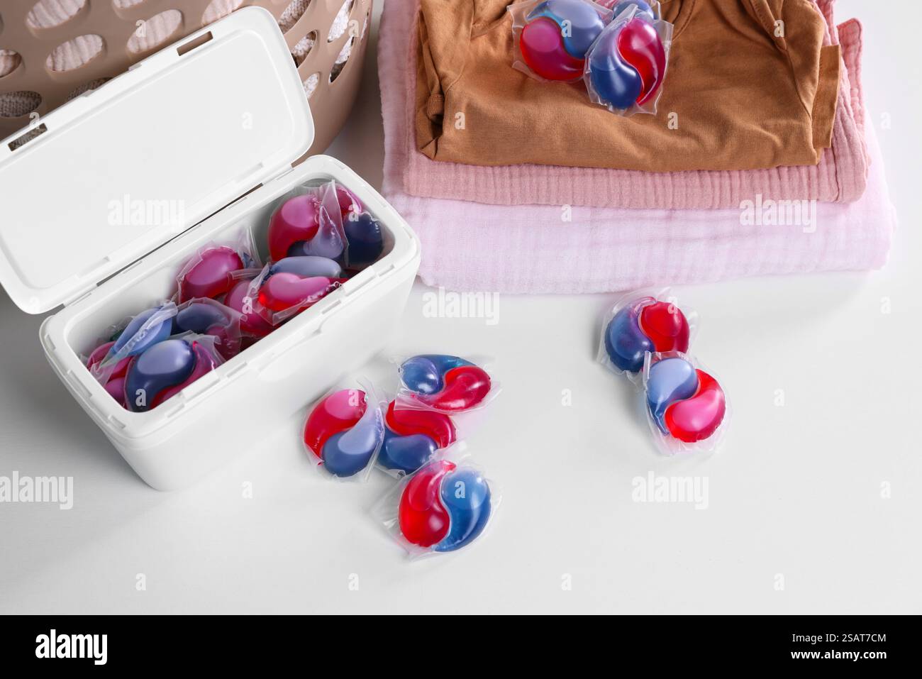 Detergent capsules and clean laundry on white background Stock Photo ...