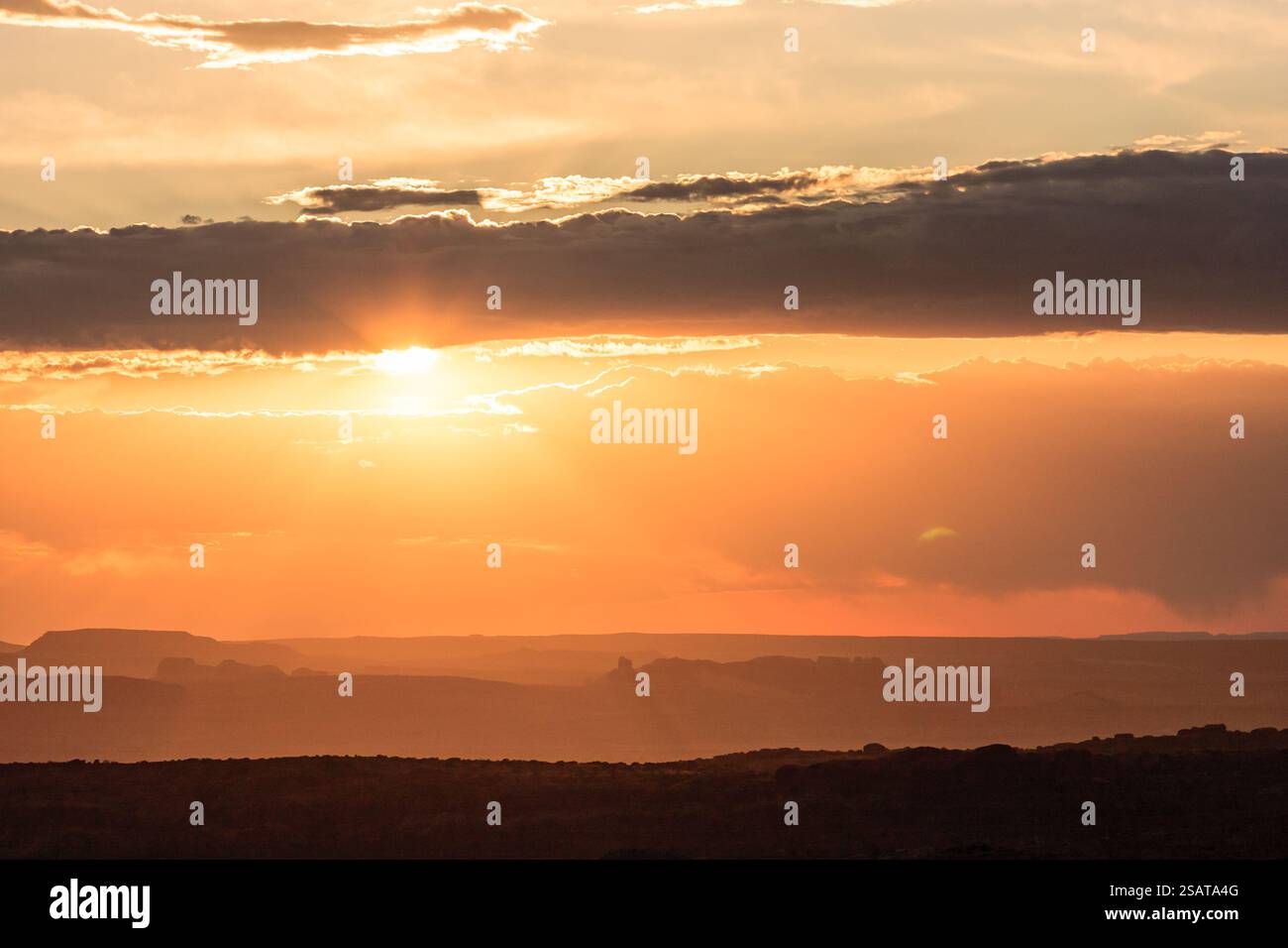 The sun is setting over a mountain range, casting a warm glow over the ...