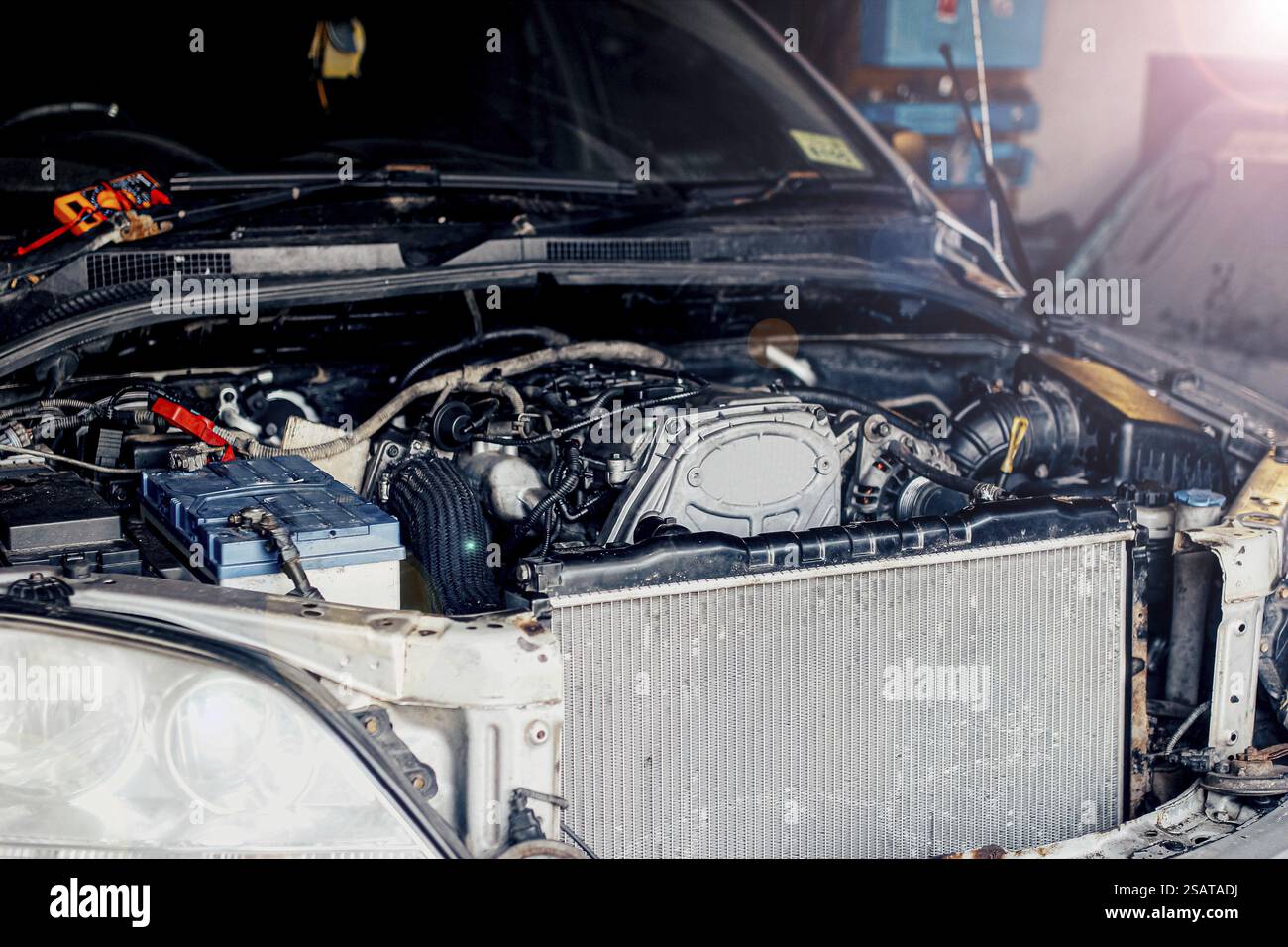 Car with the hood open showing the engine bay and battery in a workshop ...