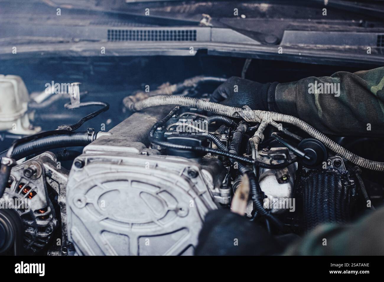 Mechanic in gloves working on an engine, adjusting cables and ...