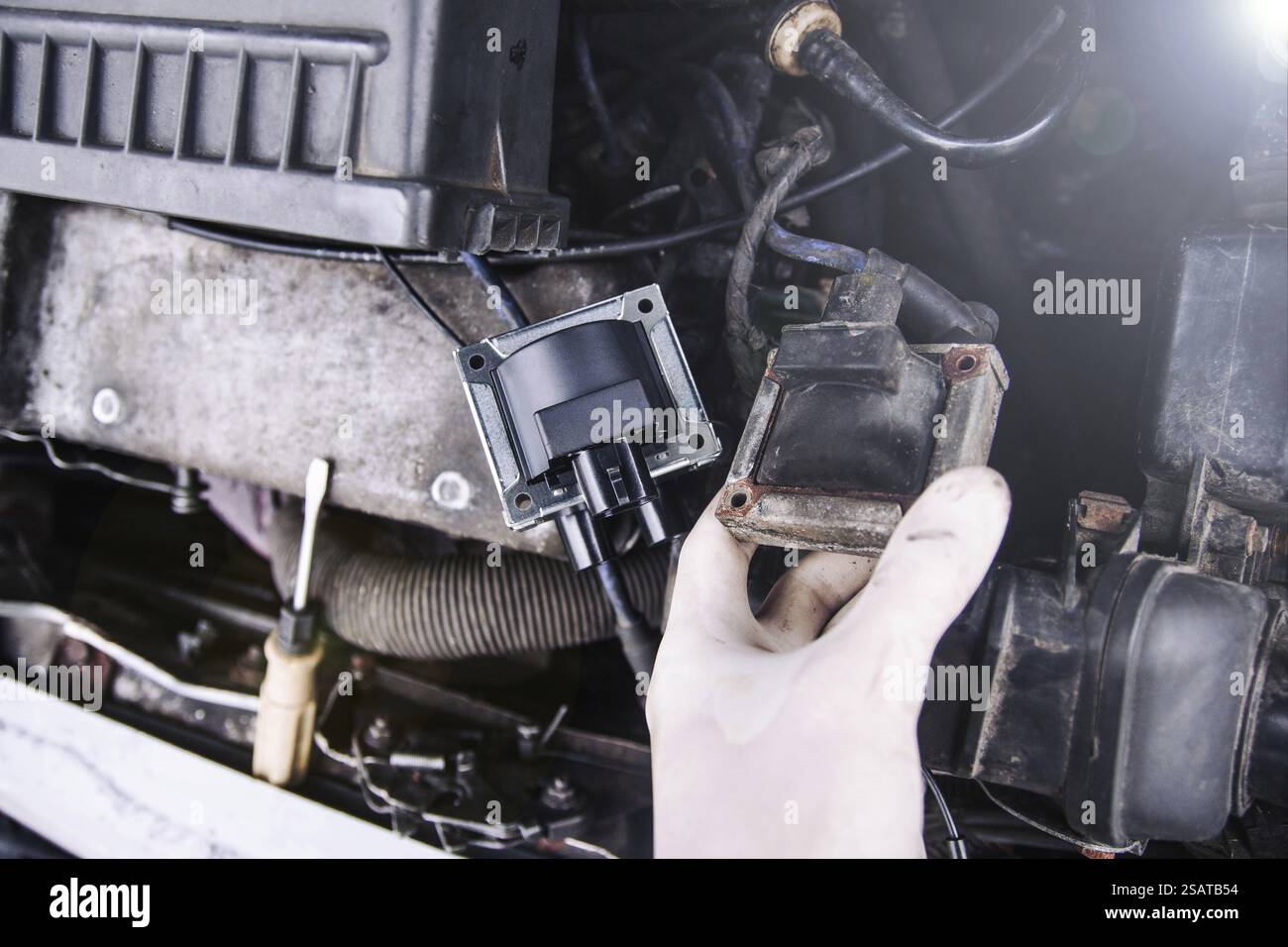 Worn gloved hand showing ignition coil inside engine compartment Stock ...
