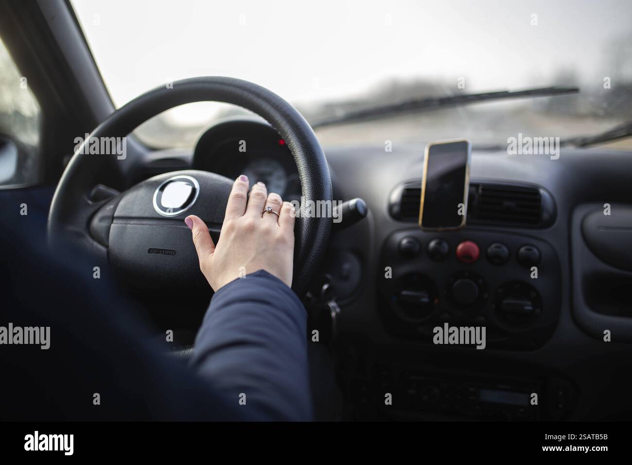 Hand on steering wheel with phone embedded on dashboard, interior view ...