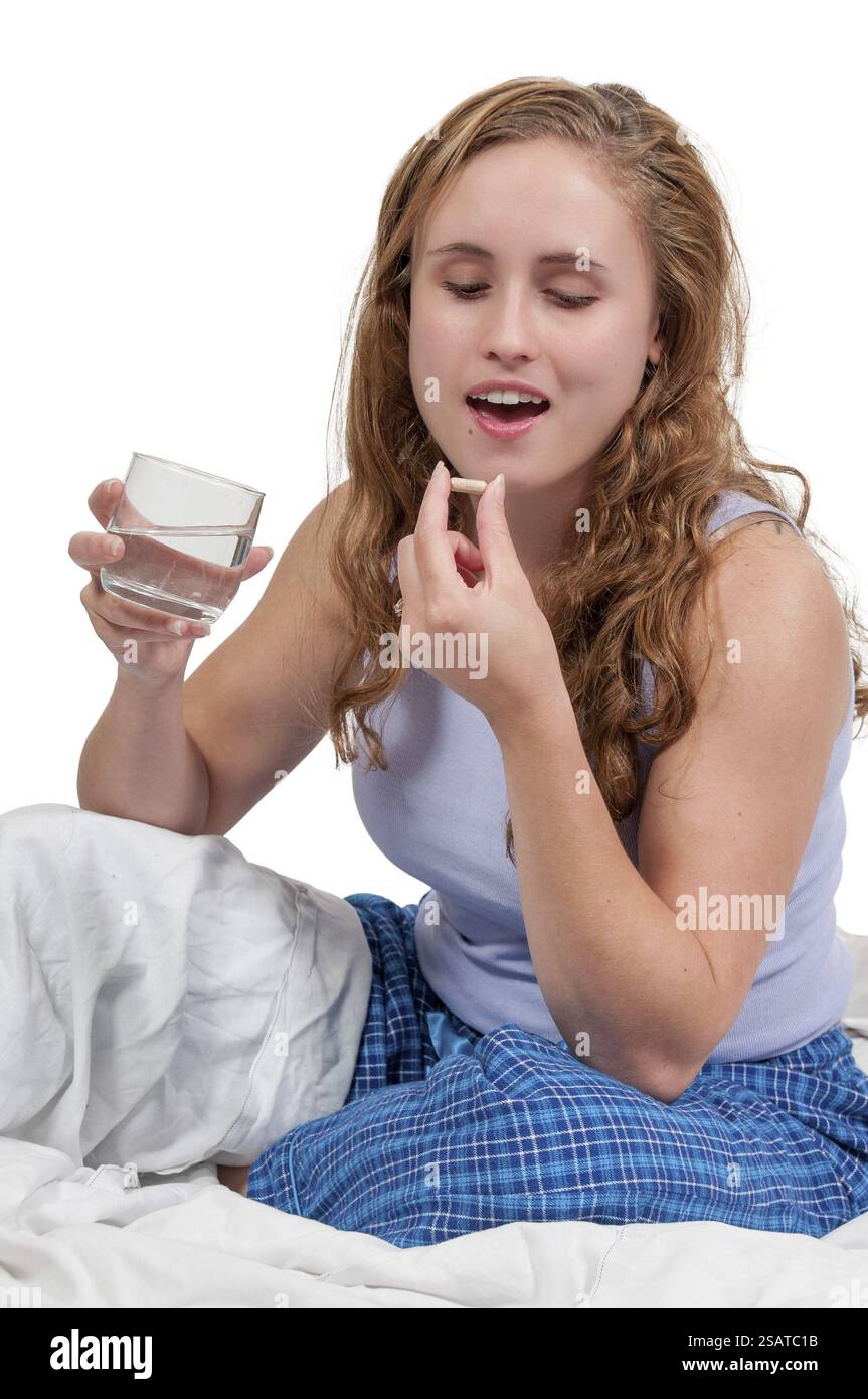 Beautiful woman taking a pill in bed Stock Photo - Alamy
