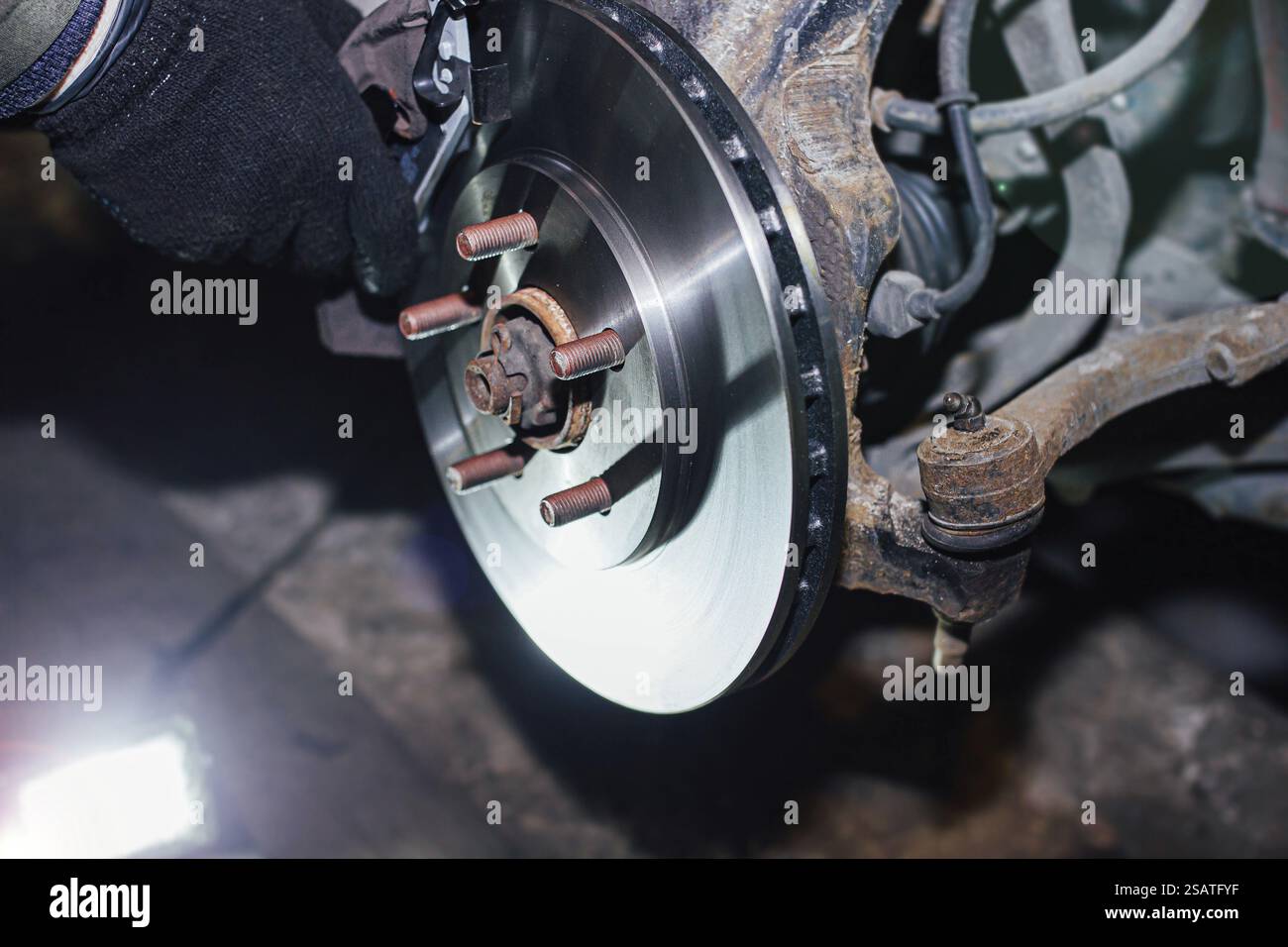 Mechanic inspecting a car brake disc with a focus on rusted components ...