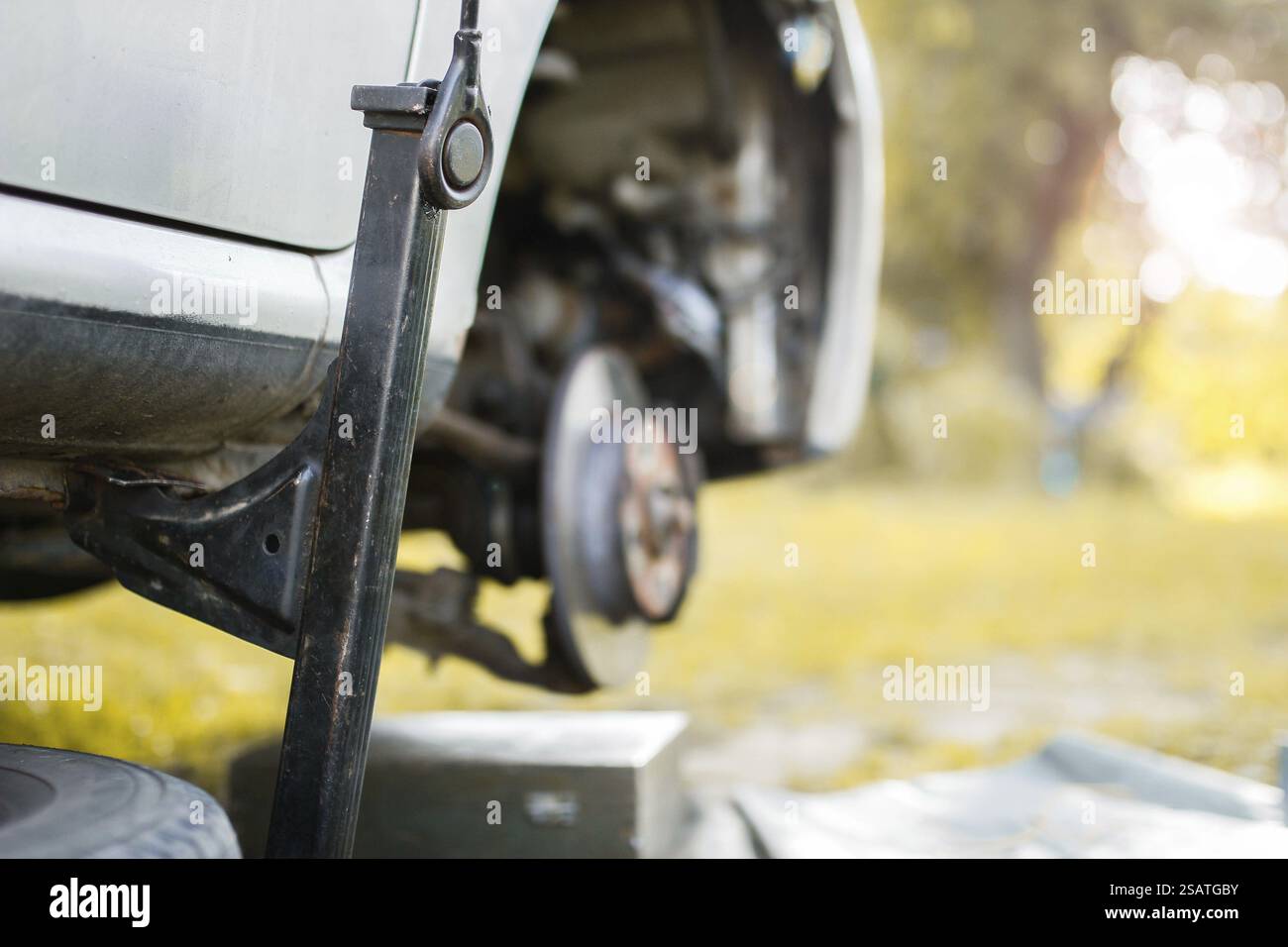 Car on a jack stand with brake disc visible and grassy background Stock ...