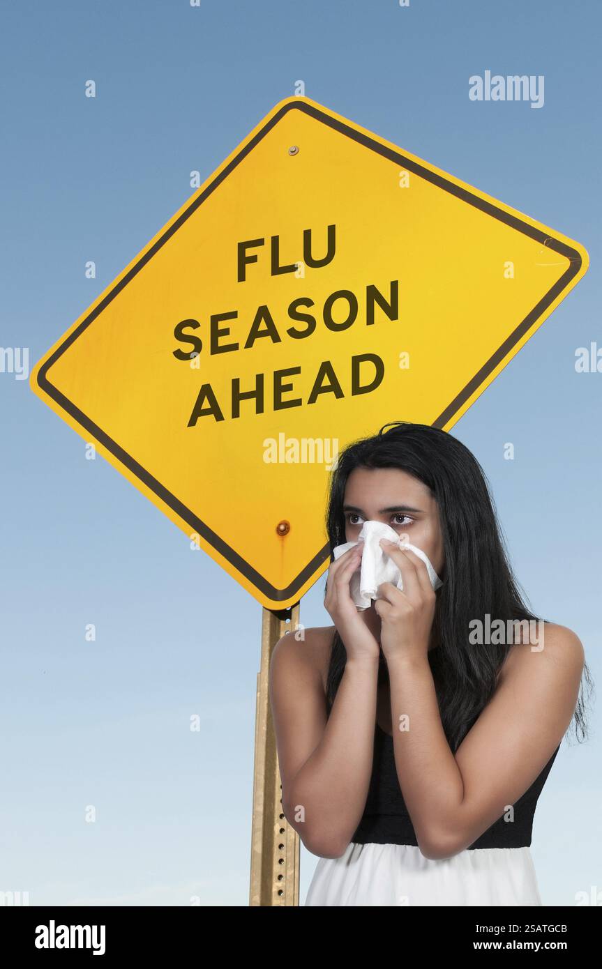 Beautiful woman with a cold, hay fever or allergies blowing her nose ...