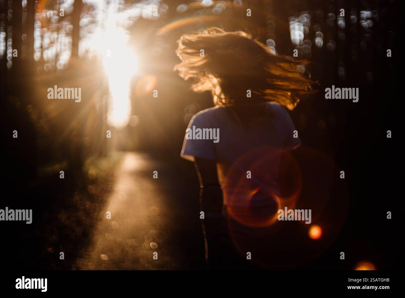 Woman in motion, hair flowing in a sunlit forest path with dynamic ...