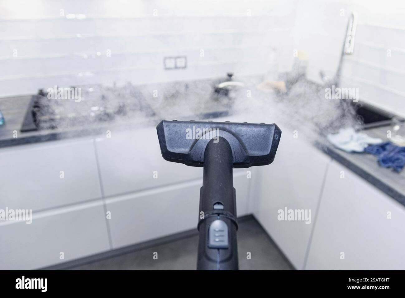 Steam cleaning a kitchen surface with white cabinets Stock Photo - Alamy
