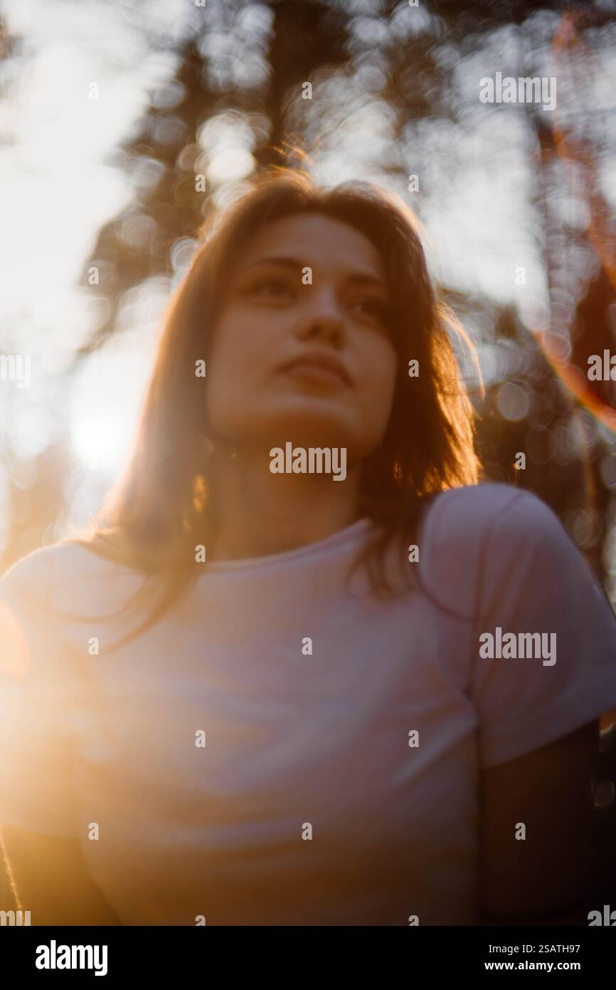 Woman gazing under soft sunlight in a dreamy forest environment Stock ...
