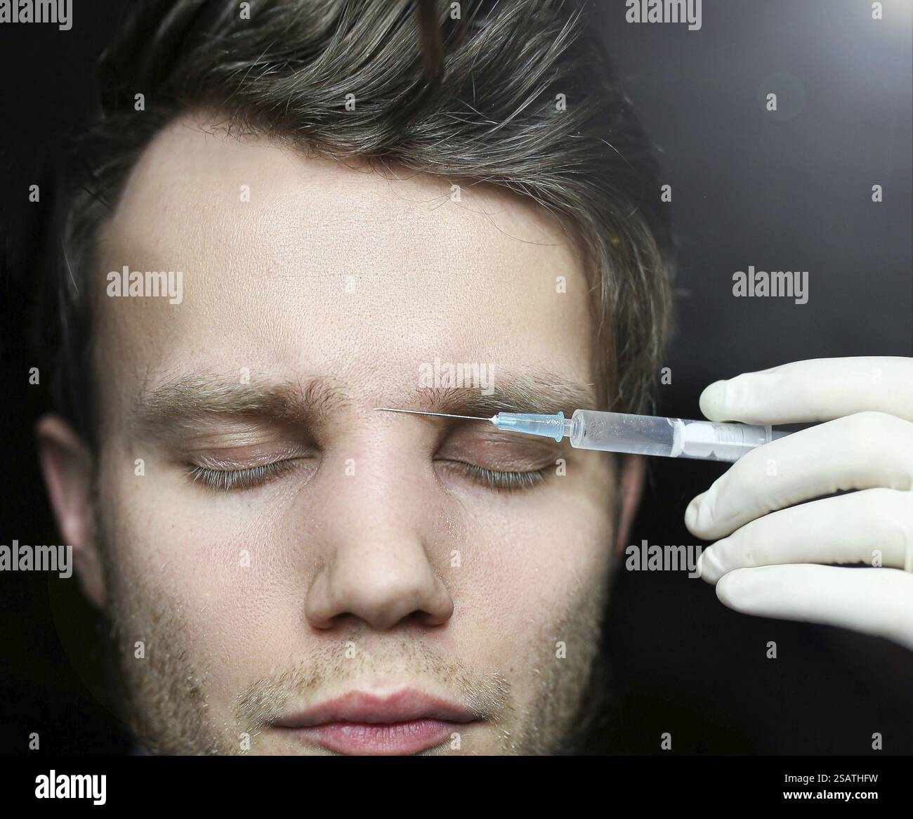 With calm expression and closed eyes, a syringe approaches a man's ...