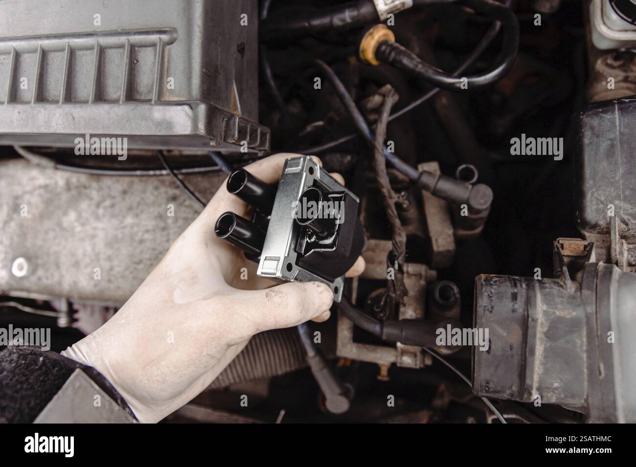 Hand holds a car part inside an engine bay showing mechanical ...
