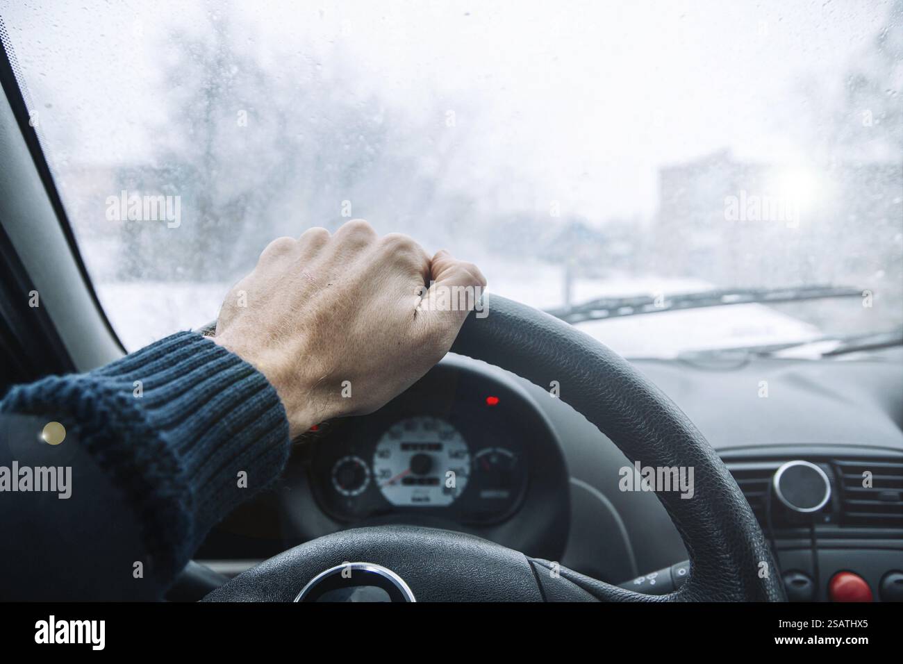 View from inside a car with steered hand, facing misty weather outside ...