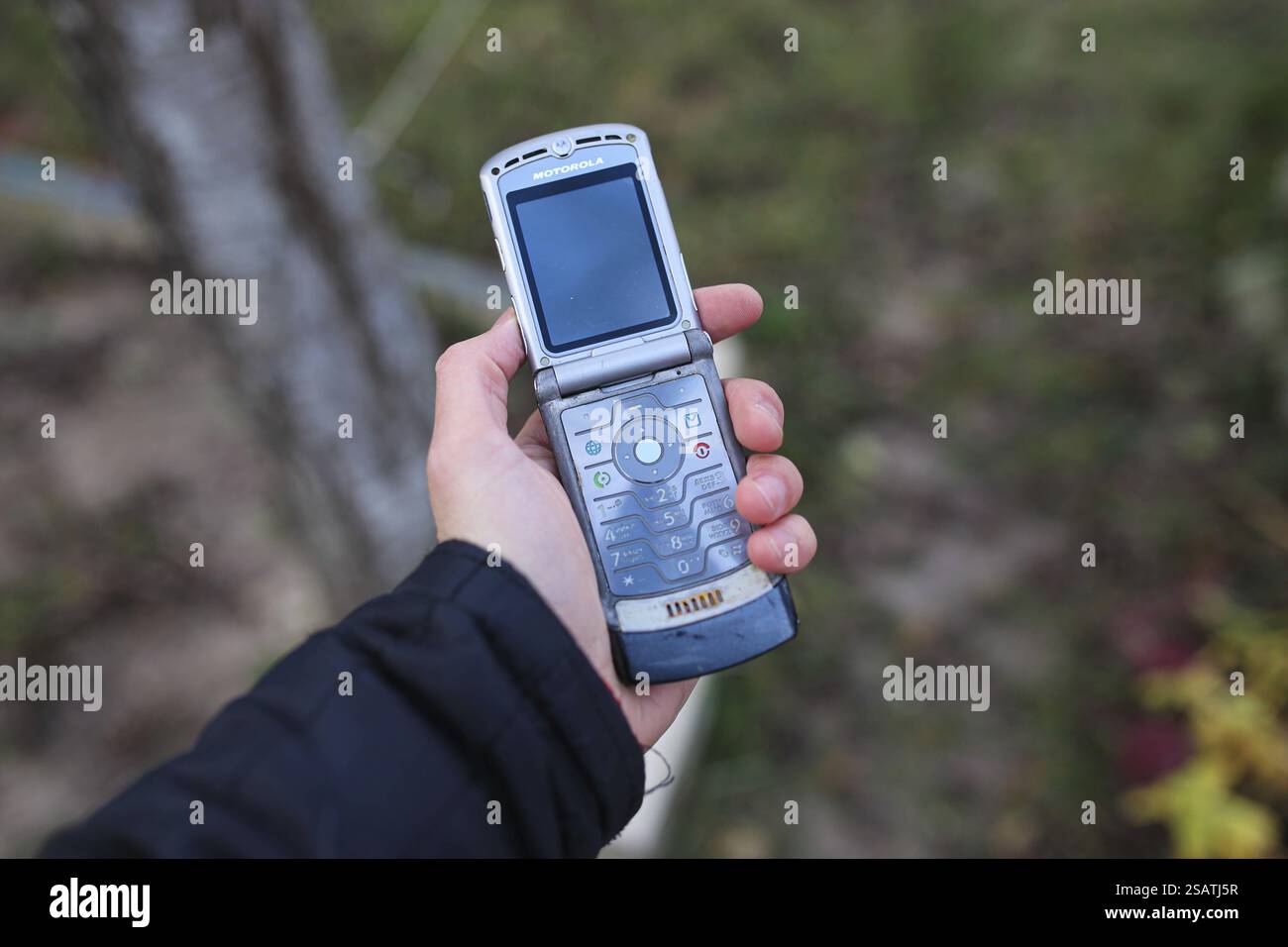 A hand holding an open Motorola flip phone with keypad facing upwards ...