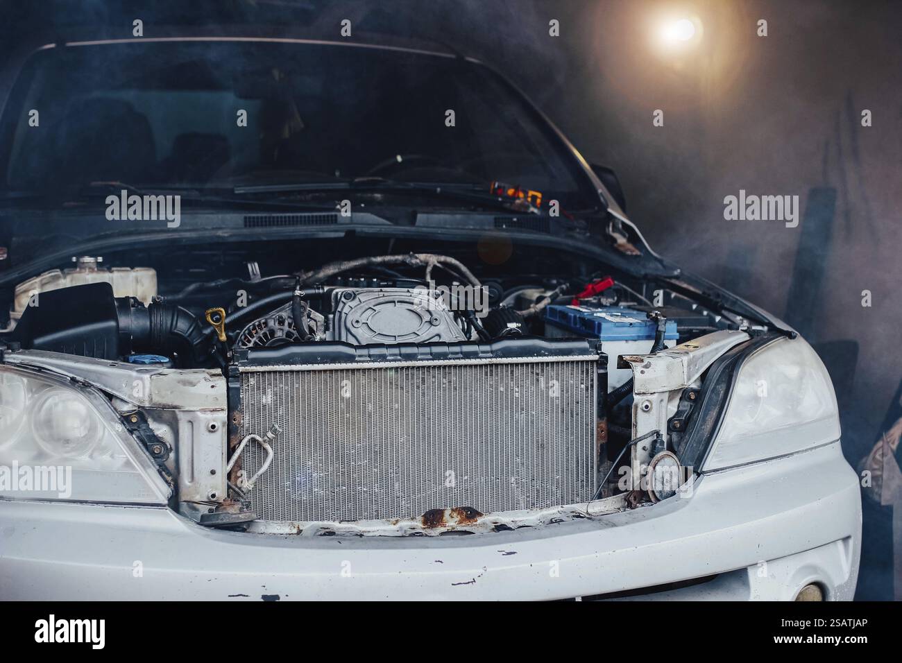 Car with its hood open revealing the engine amidst a foggy environment ...