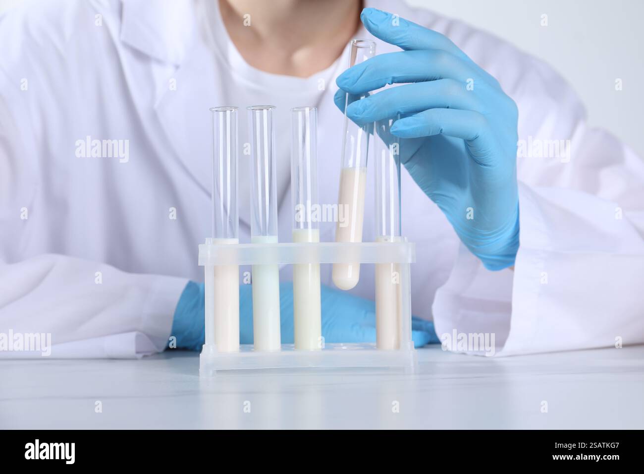 Laboratory testing. Scientist working with test tubes at white marble ...