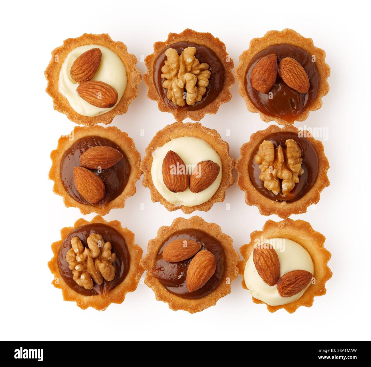Assorted mini pastries topped with nuts arranged in a neat grid on a ...