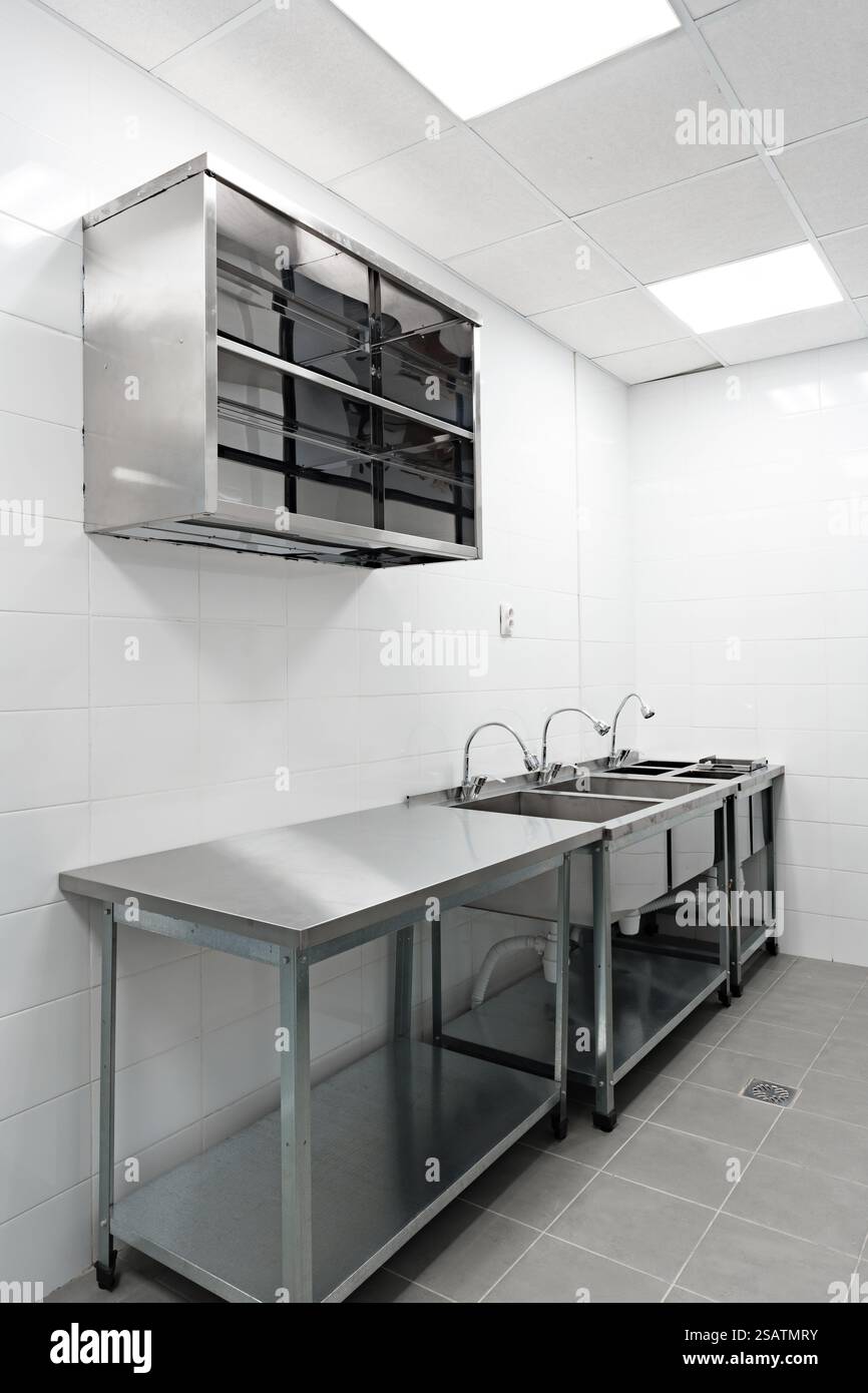Clean stainless steel kitchen setup with washing stations and ample ...