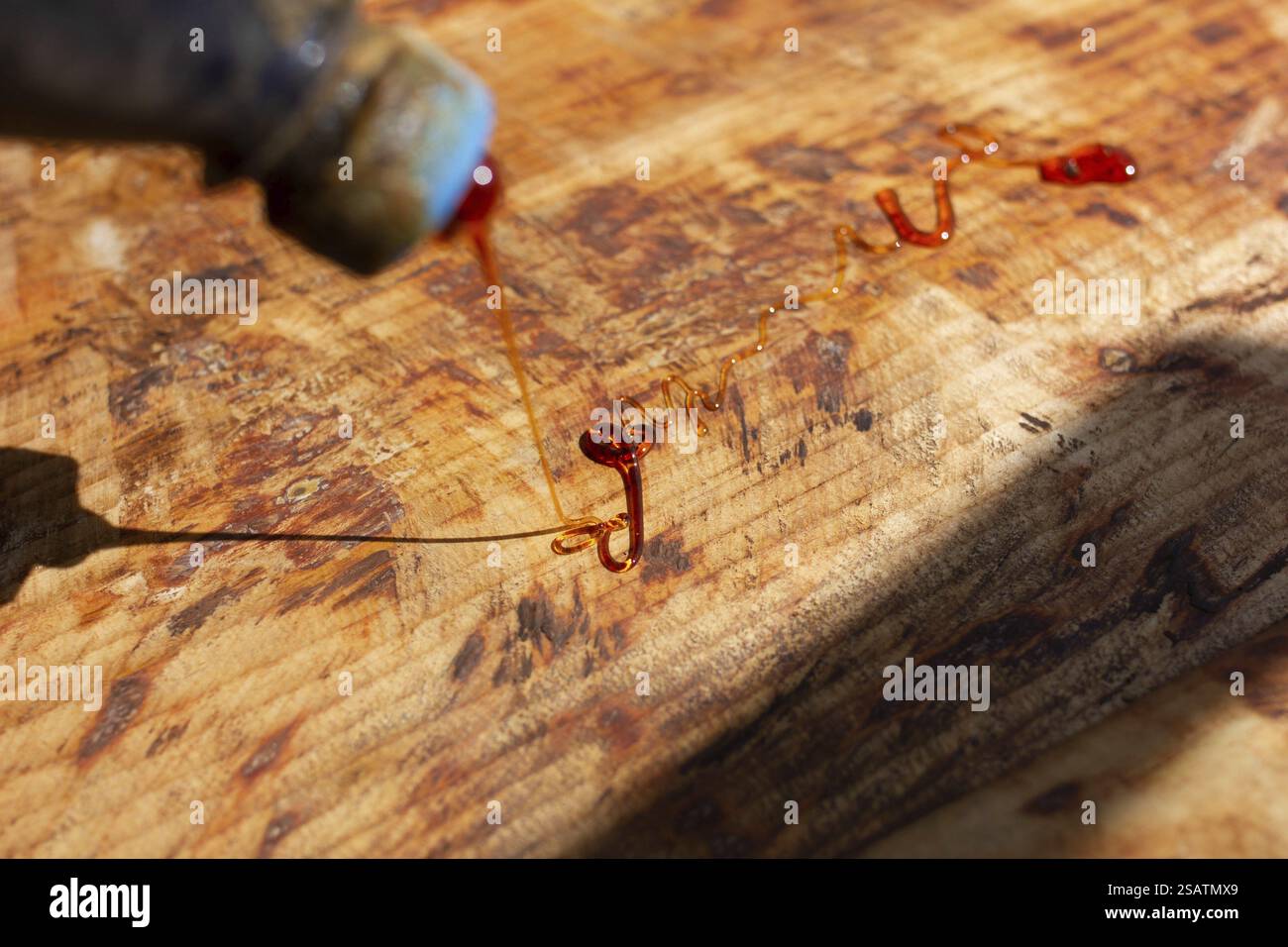 Varnish dripping onto a sunlit wooden surface, revealing rich wood ...