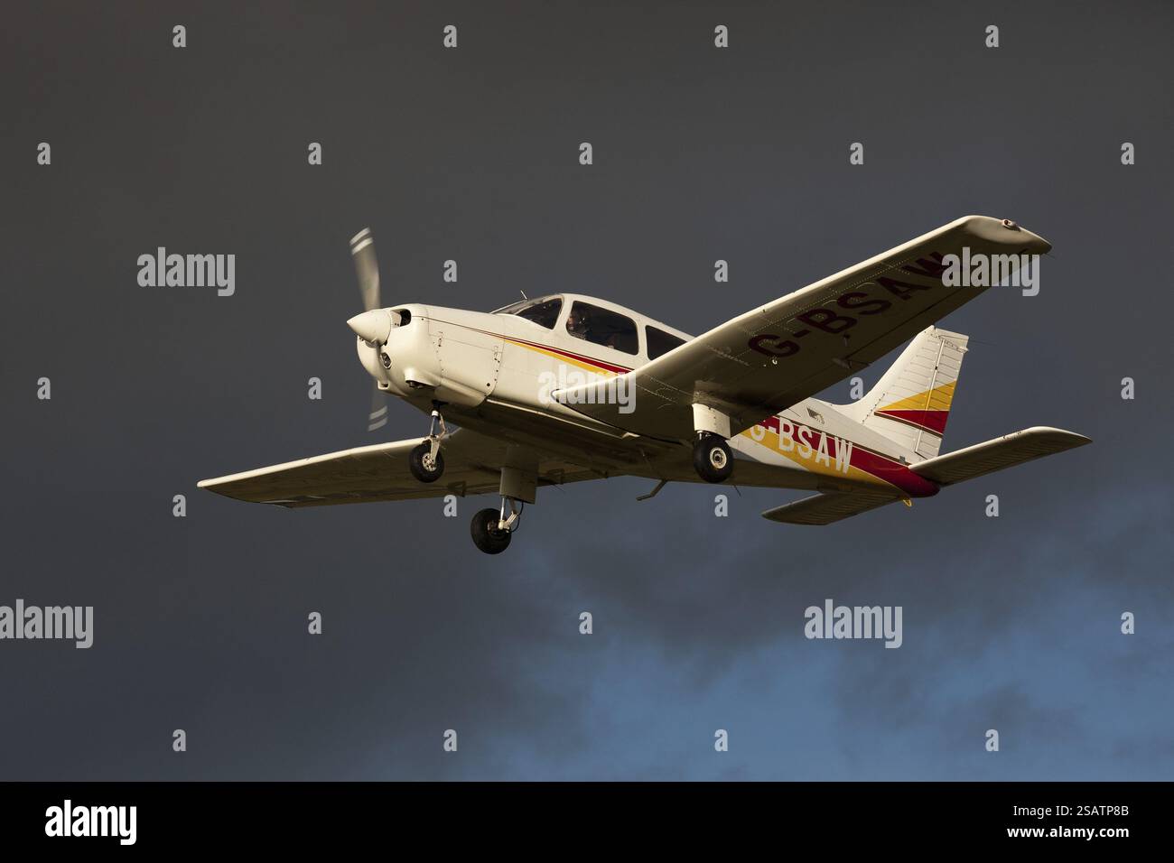 A Piper PA28 single-engine airplane with propeller flying under dark ...