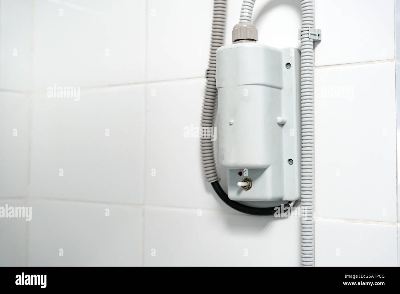 Electric shower unit mounted on tiled bathroom wall showing design ...