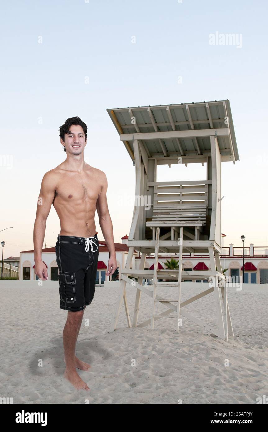 Male lifeguard standing on the beach by a lifeguard stand Stock Photo ...