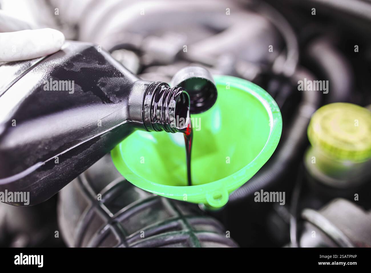 Engine oil being poured into a car engine using a green funnel Stock ...