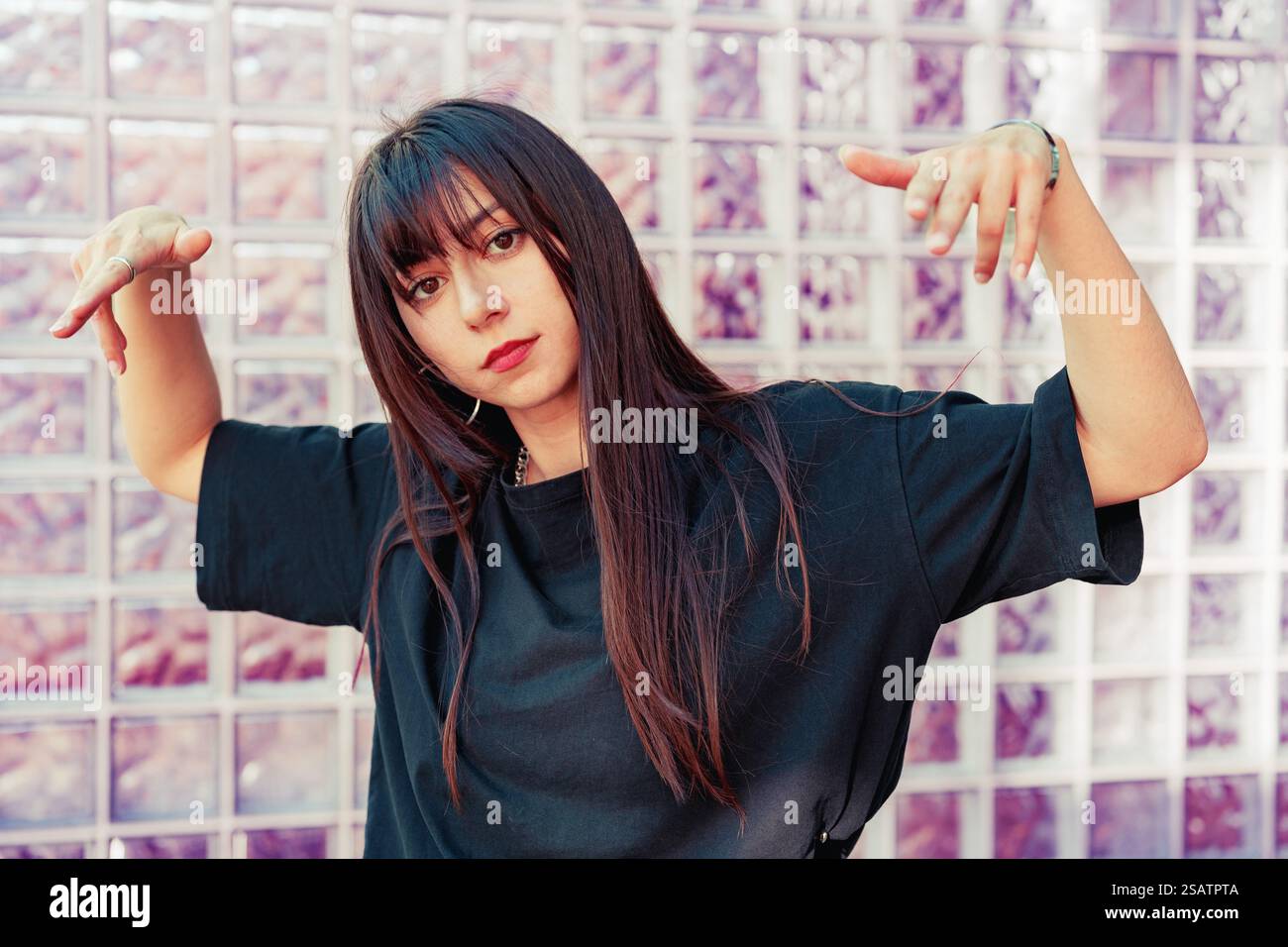 Young woman poses playfully in front of a textured glass wall during ...