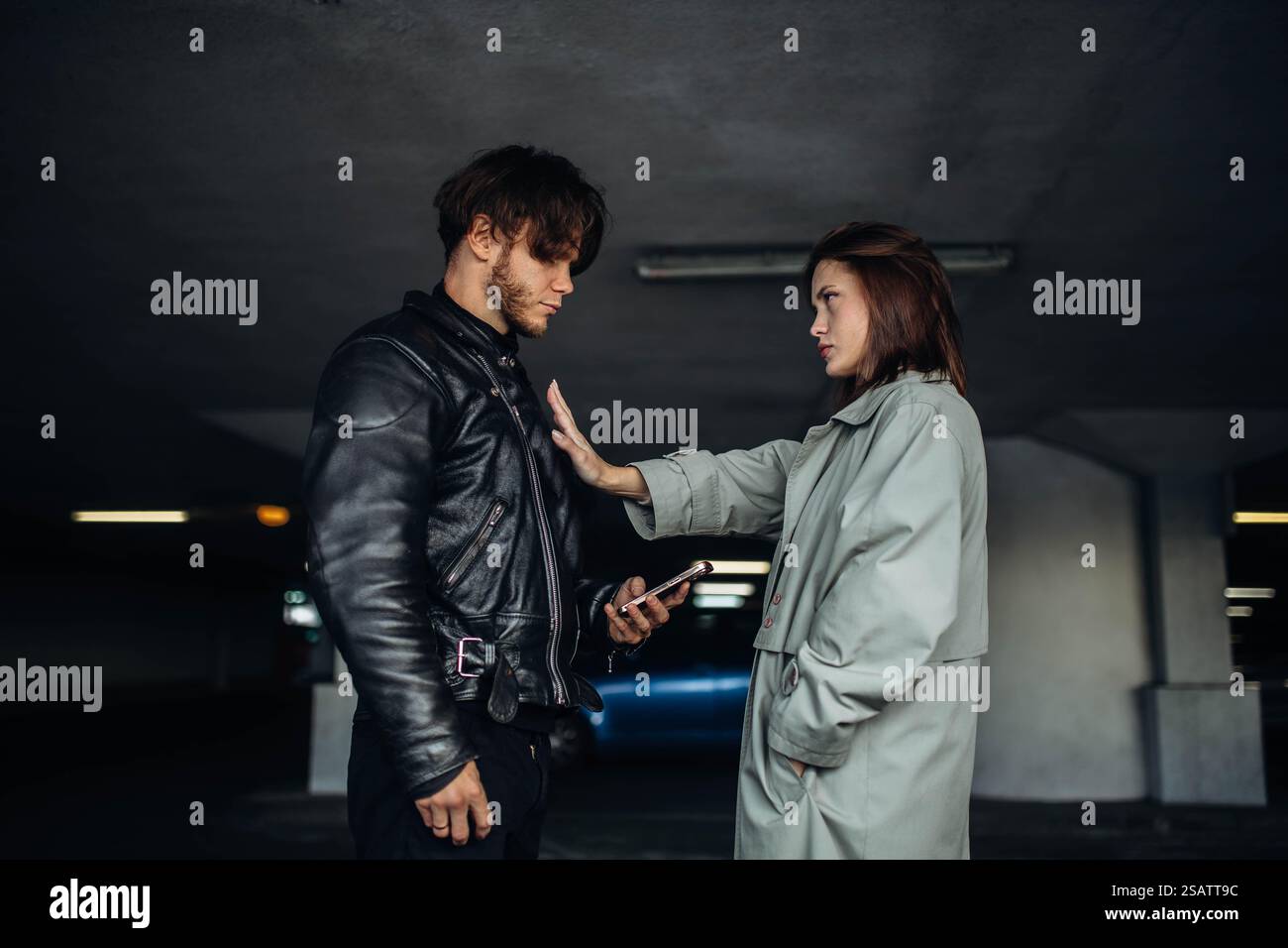A man and woman face each other in an underground parking garage, the ...