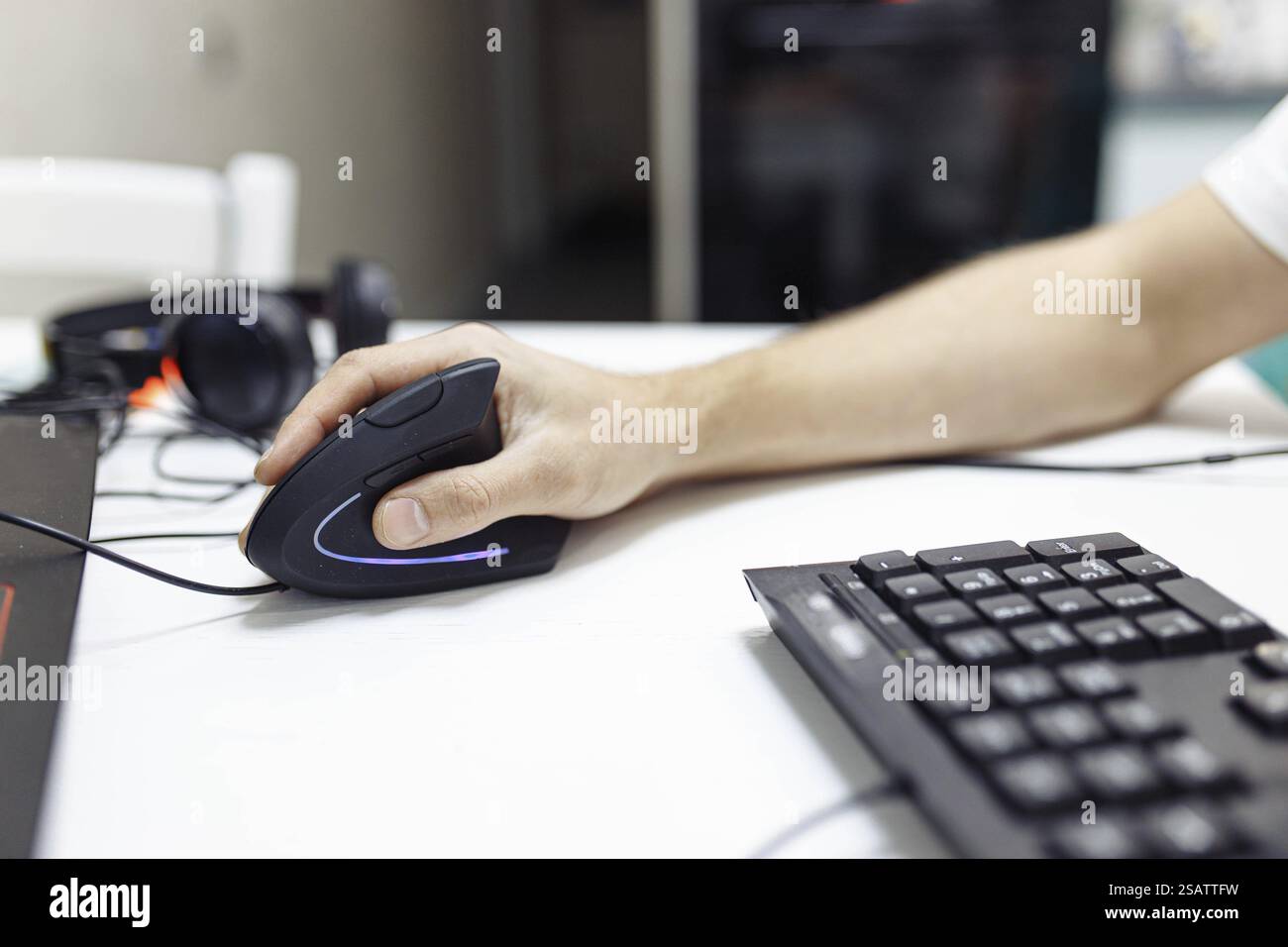 A hand using an ergonomic mouse on a desk next to a keyboard Stock ...