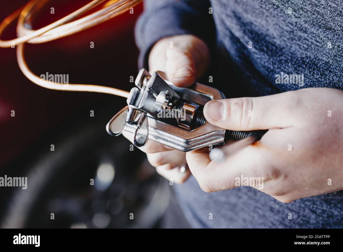 Close-up of hands handling a tool with copper wires in a mechanical ...