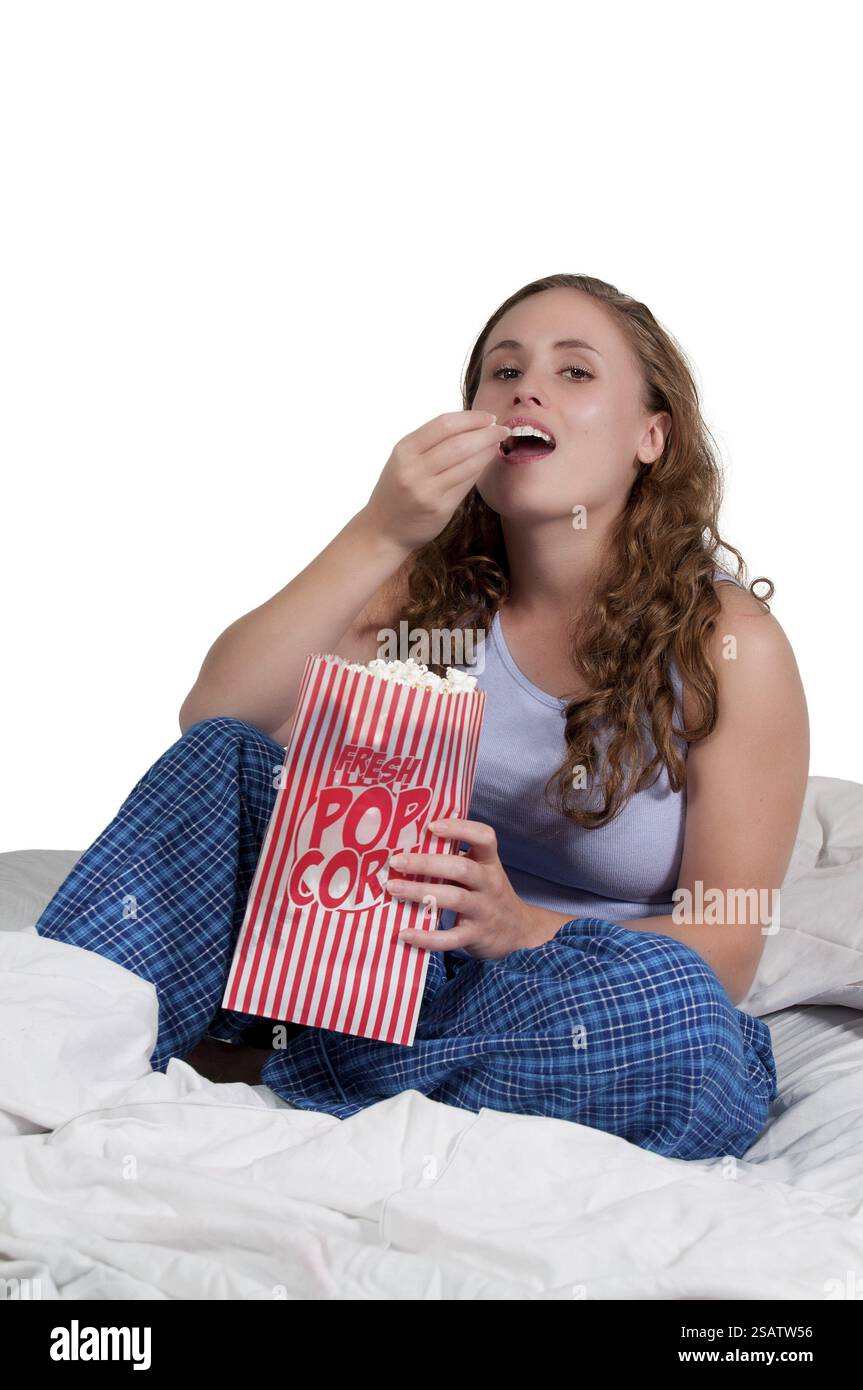 Beautiful young woman eating popcorn in bed Stock Photo - Alamy