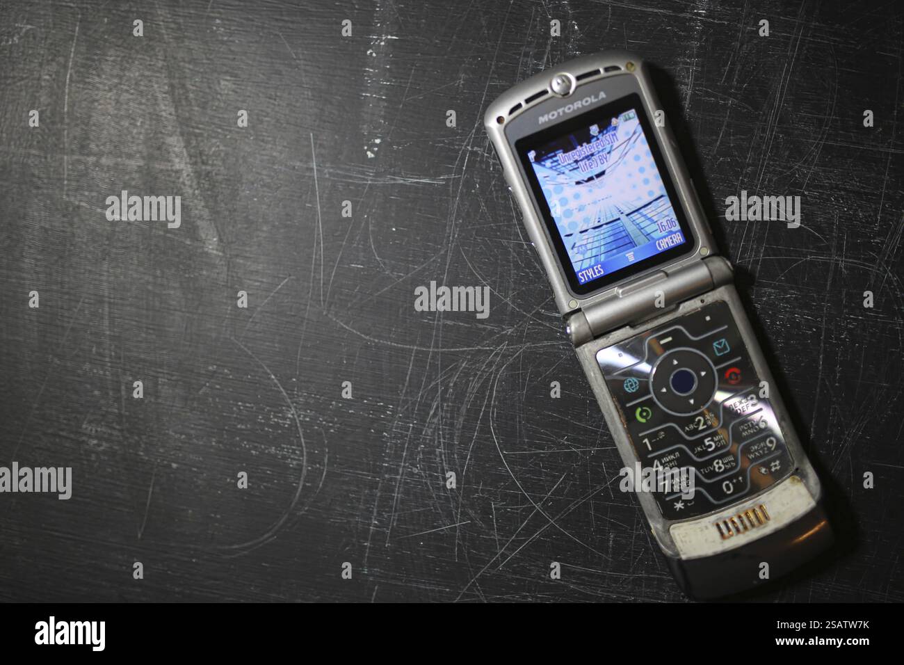 A Motorola flip phone open on a black textured surface showing the ...