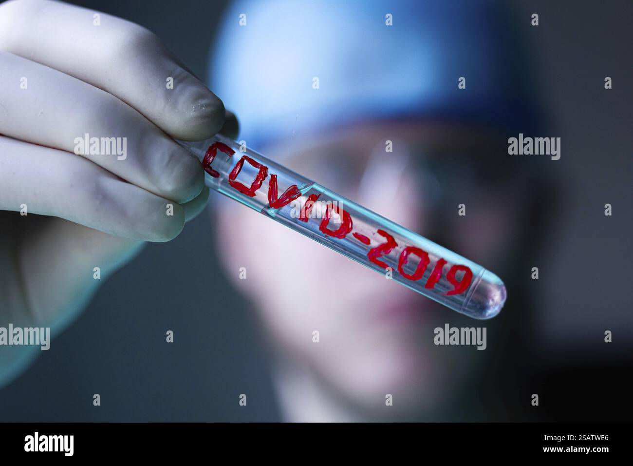 Blurred figure holding test tube labeled COVID-2019 Stock Photo - Alamy