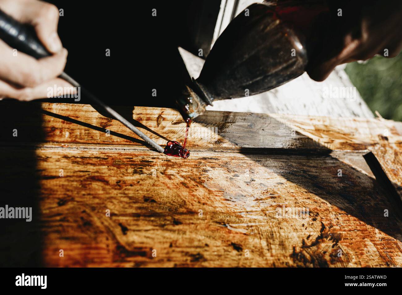 Oil or liquid being applied to wood surface with tool Stock Photo - Alamy