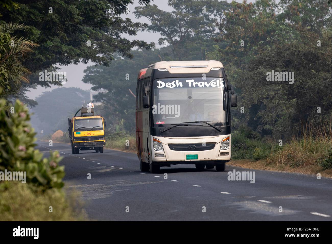A luxury bus and a truck moving along the road in Chalanbil, Pabna ...