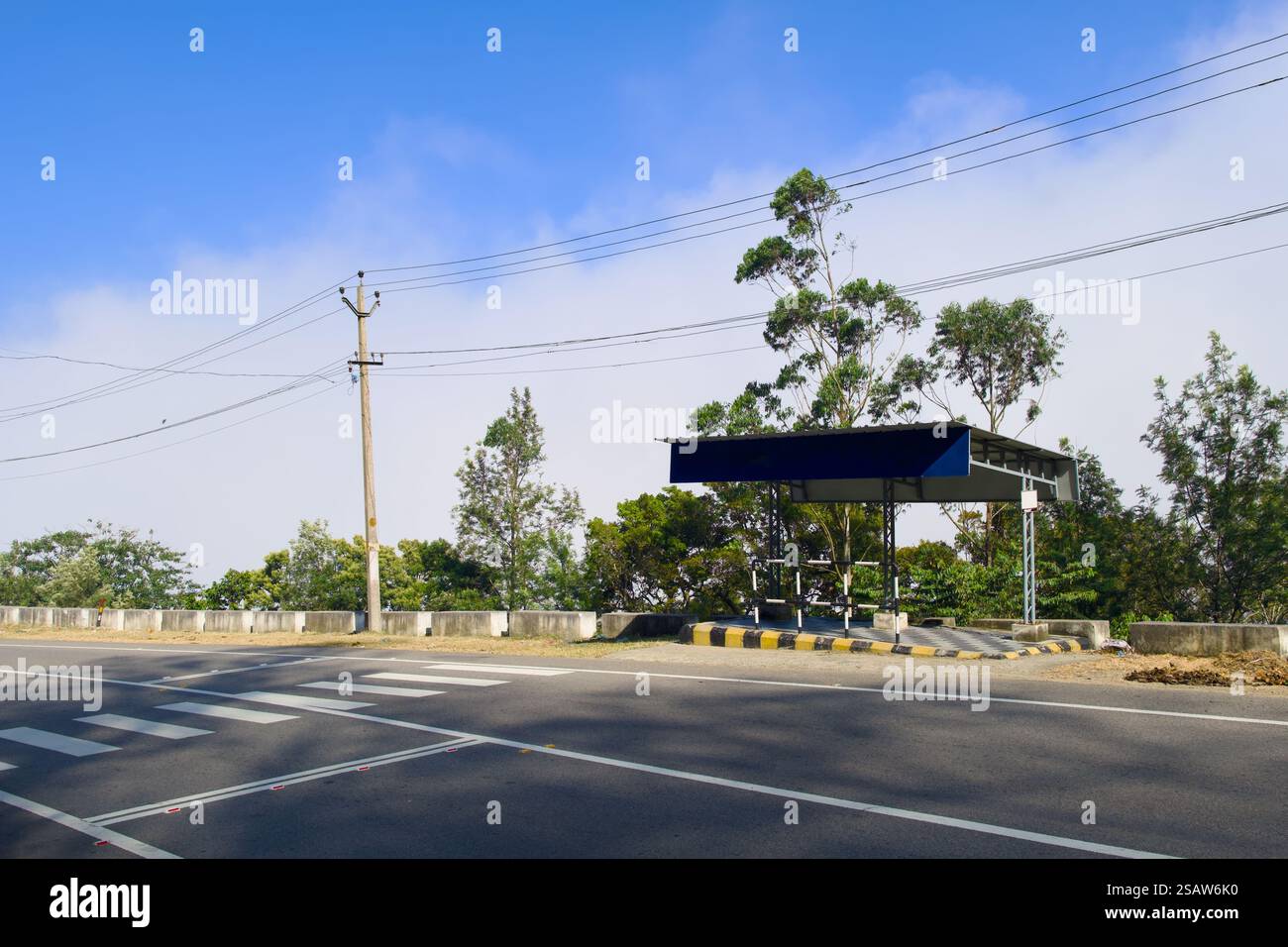 This image captures a roadside bus stop with a blue roof, situated next ...