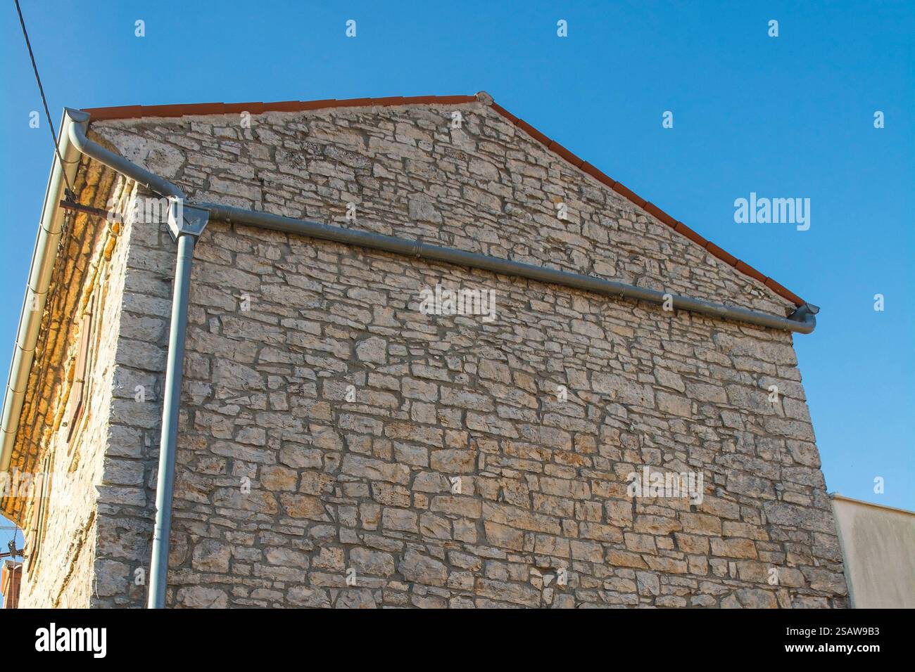Side of an old stone house showing gable roof outline of earlier 1 ...