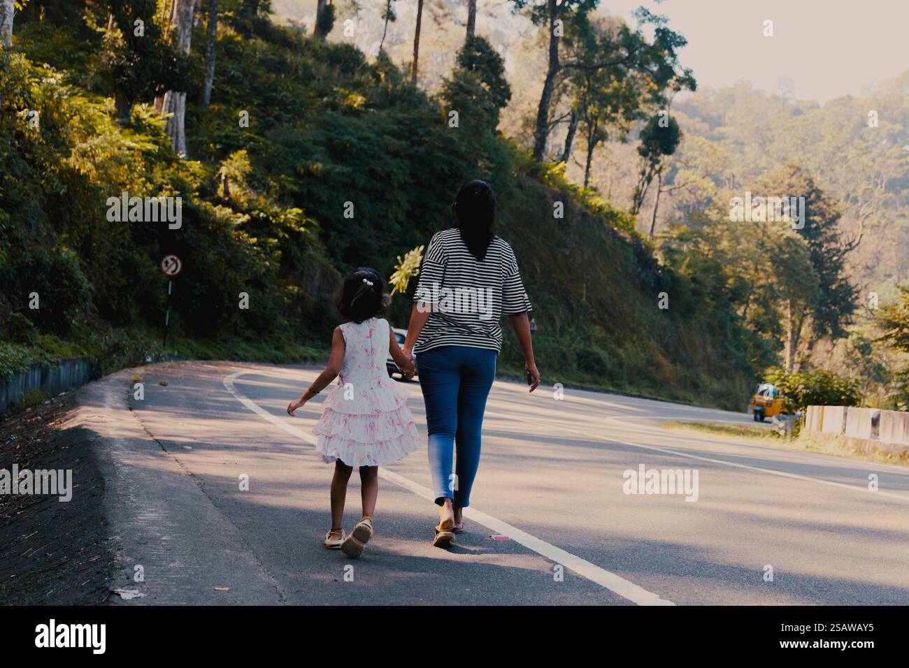 This image captures a heartwarming moment as a mother and daughter walk ...