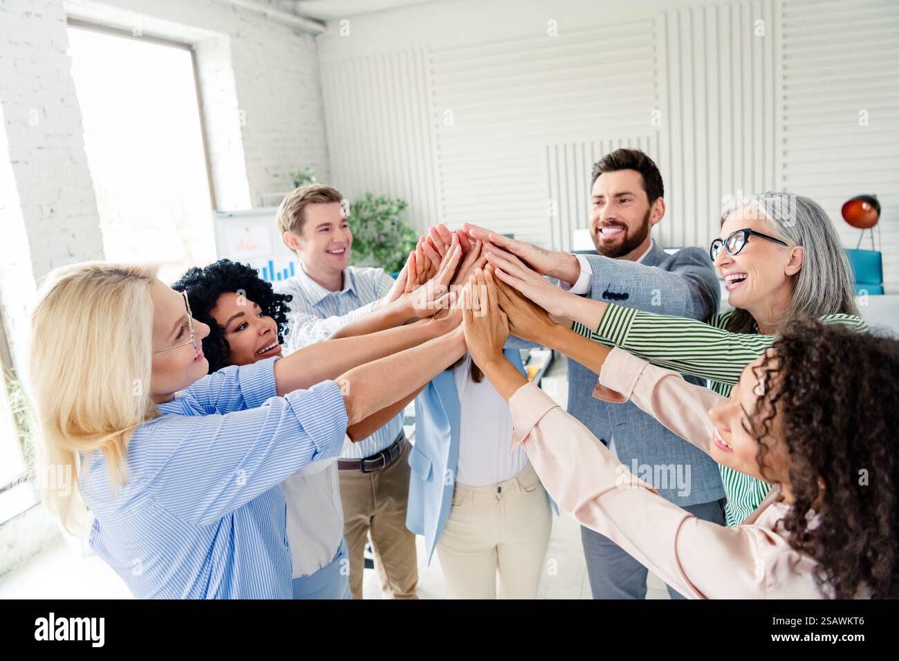 Diverse group of professionals uniting hands in a modern office setting ...