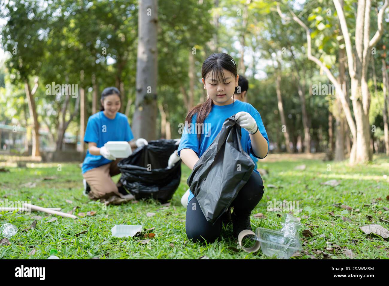 Focused family volunteers collecting garbage in a park, emphasizing ...