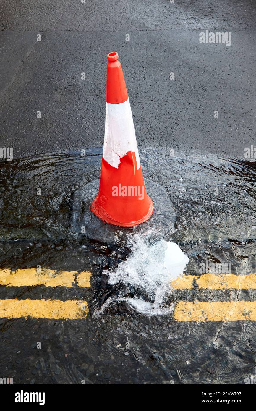 traffic cone beside water from flooding from burst fresh water main ...