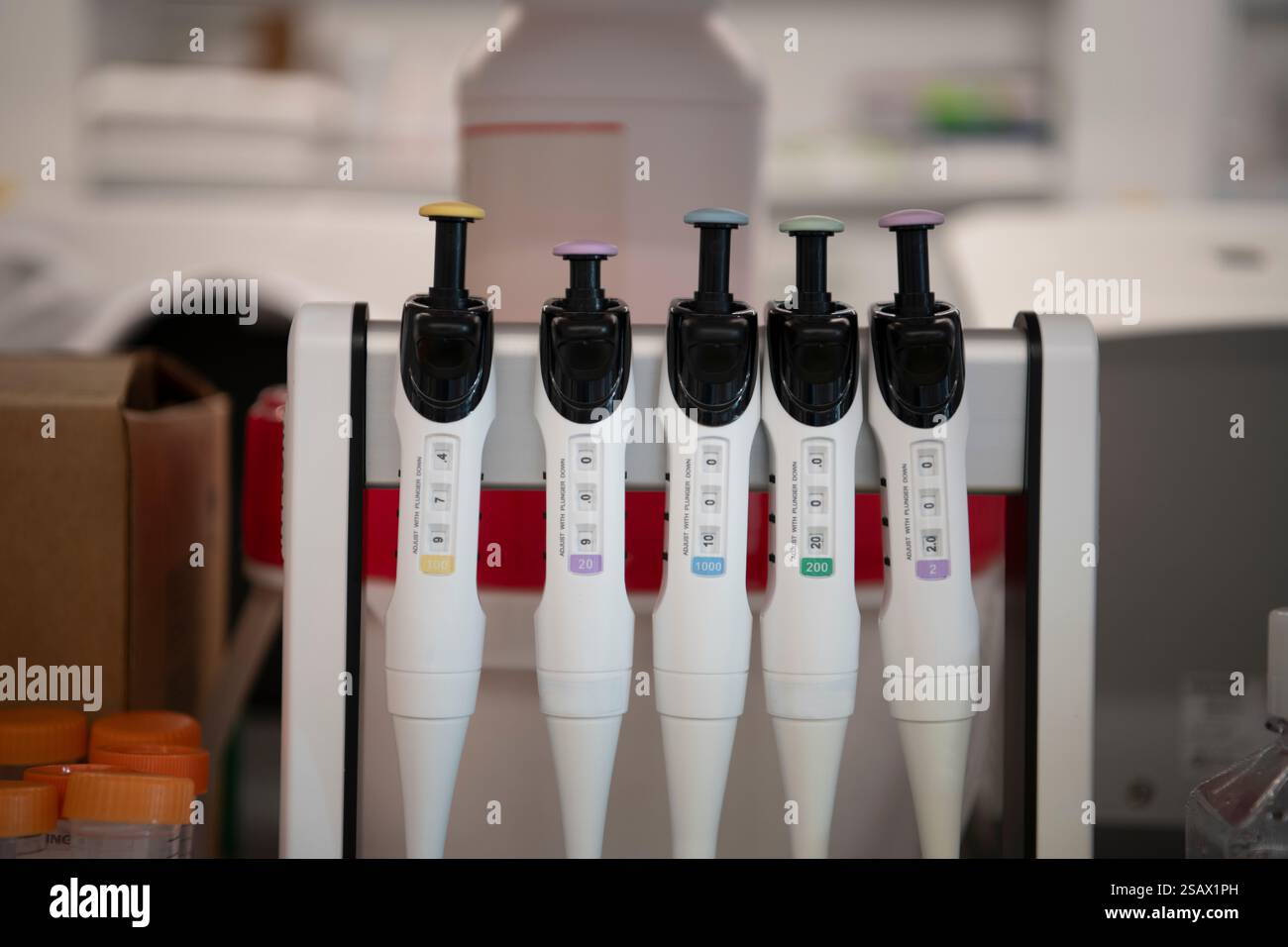 five adjustable-volume pipettes on a rack in a science medical lab ...