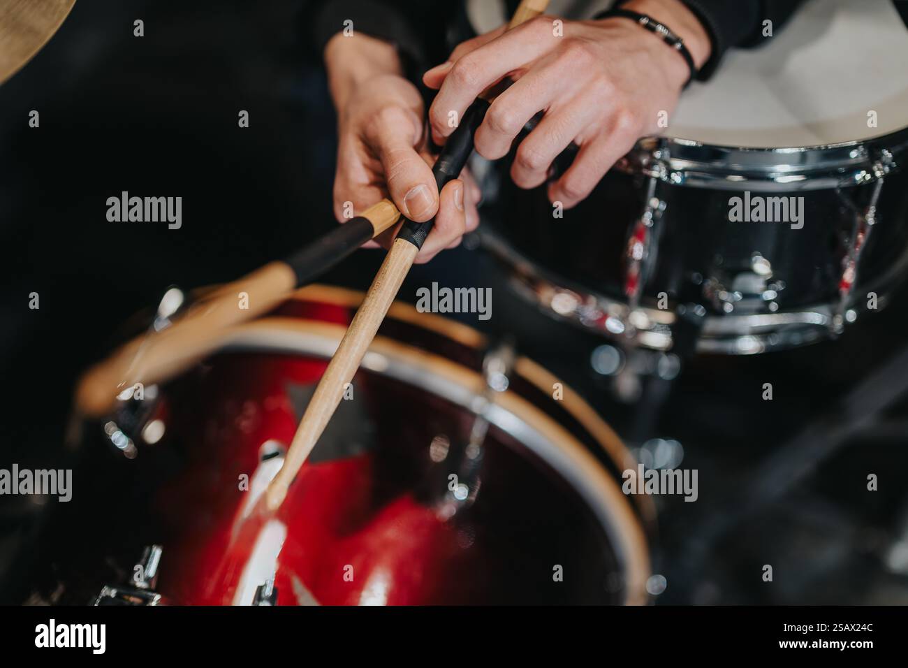 Close-up of hands playing drums with sticks on a red drum set Stock ...
